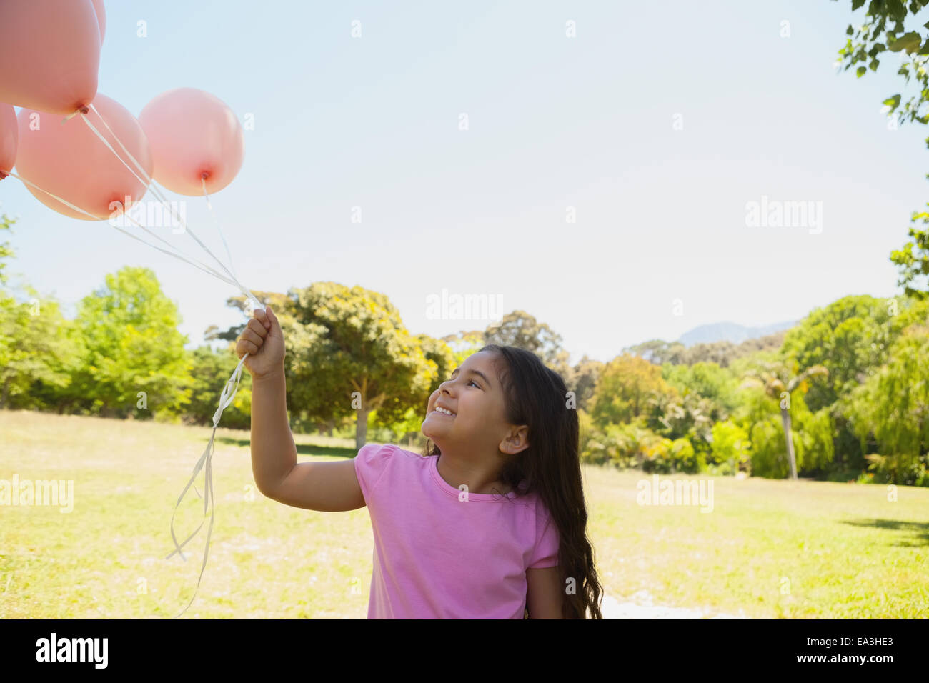 Girl playing with pink balloons at park Stock Photo - Alamy