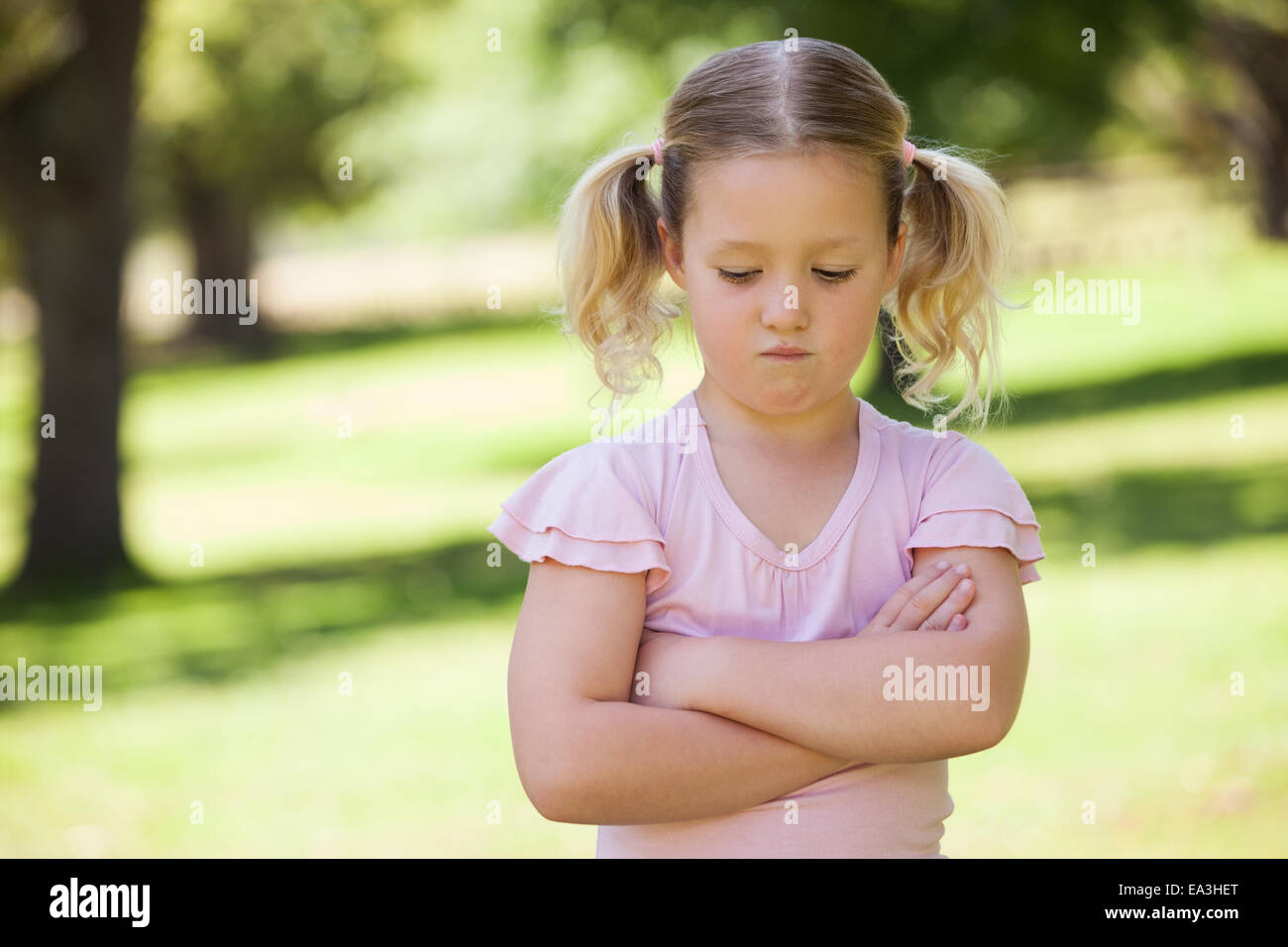 Sad young girl with arms crossed at park Stock Photo - Alamy