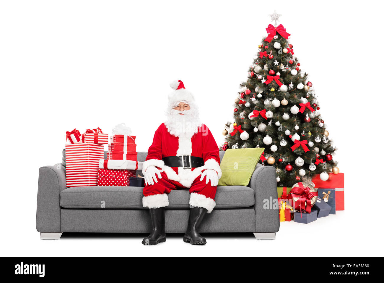 Santa sitting on a sofa by a Christmas tree isolated on white ...