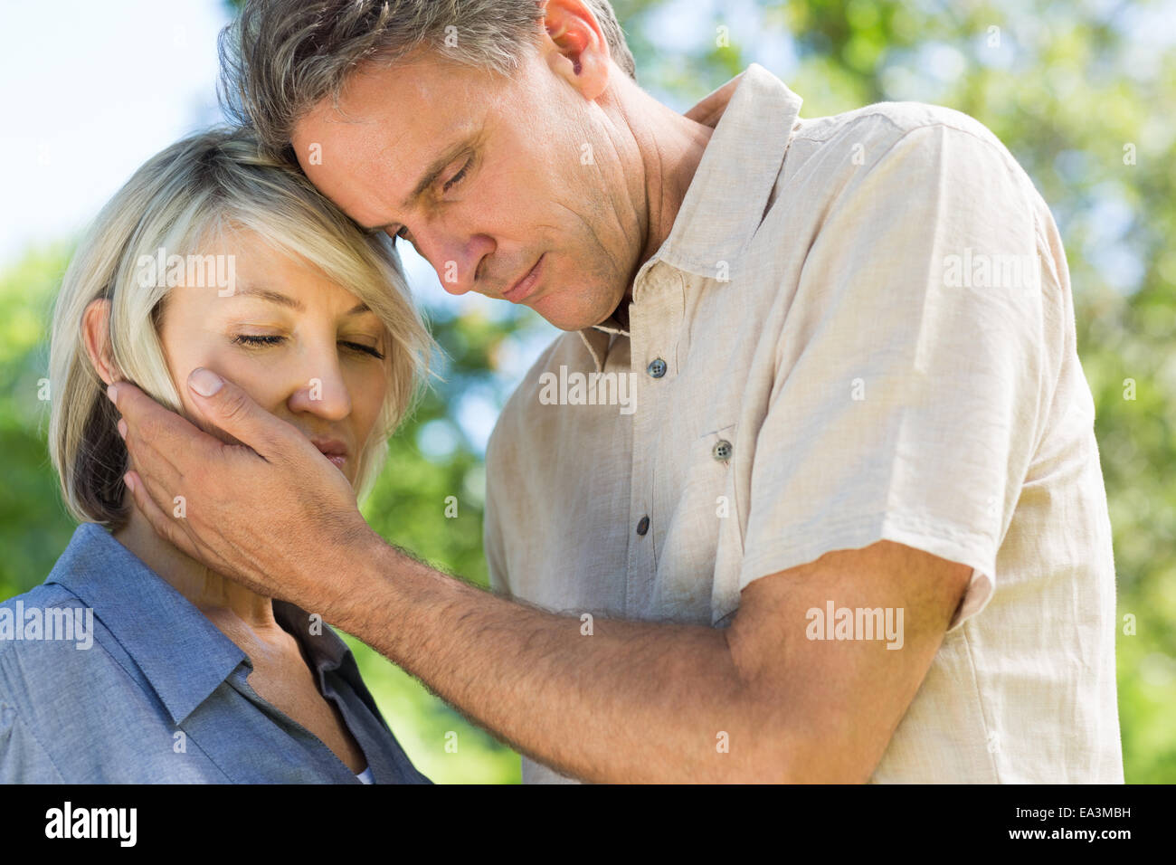 Man comforting woman in park Stock Photo - Alamy