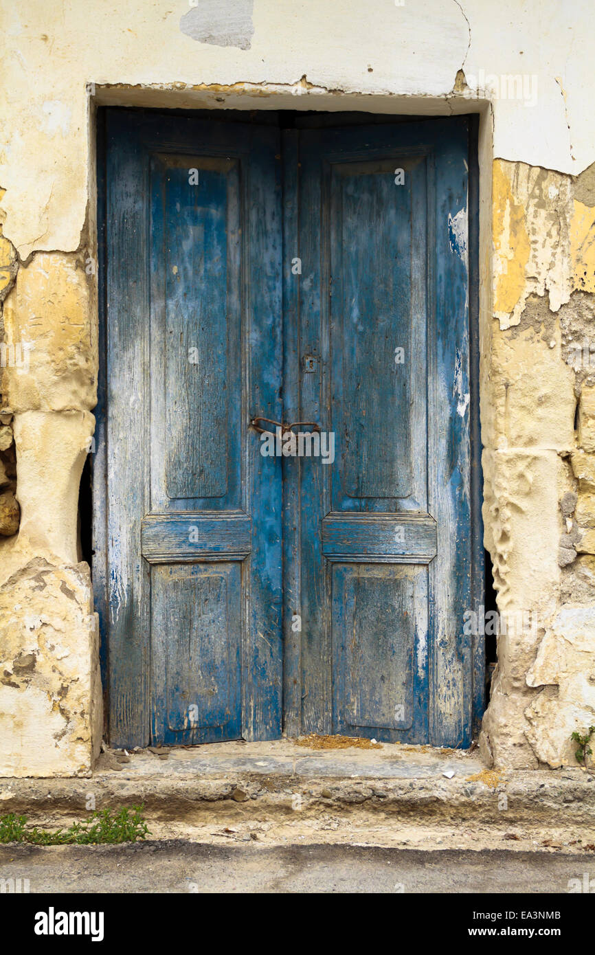 Old ruin with blue double wooden locked doors as building entrance ...
