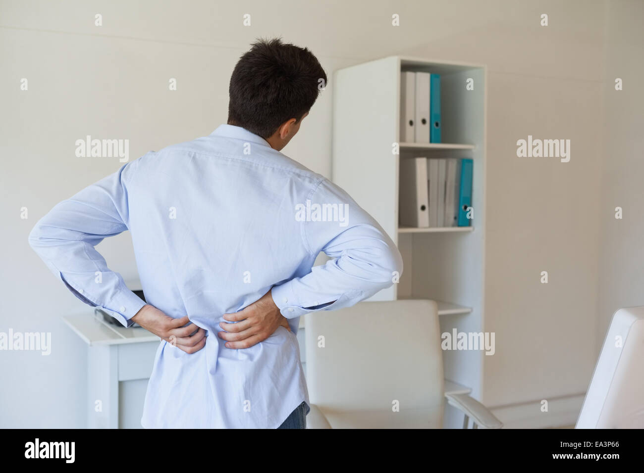 Casual businessman touching his sore back Stock Photo - Alamy