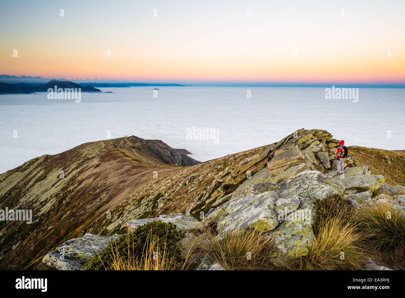 Hiker walking down on mountain ridge during twilight. Last sunlight on ...