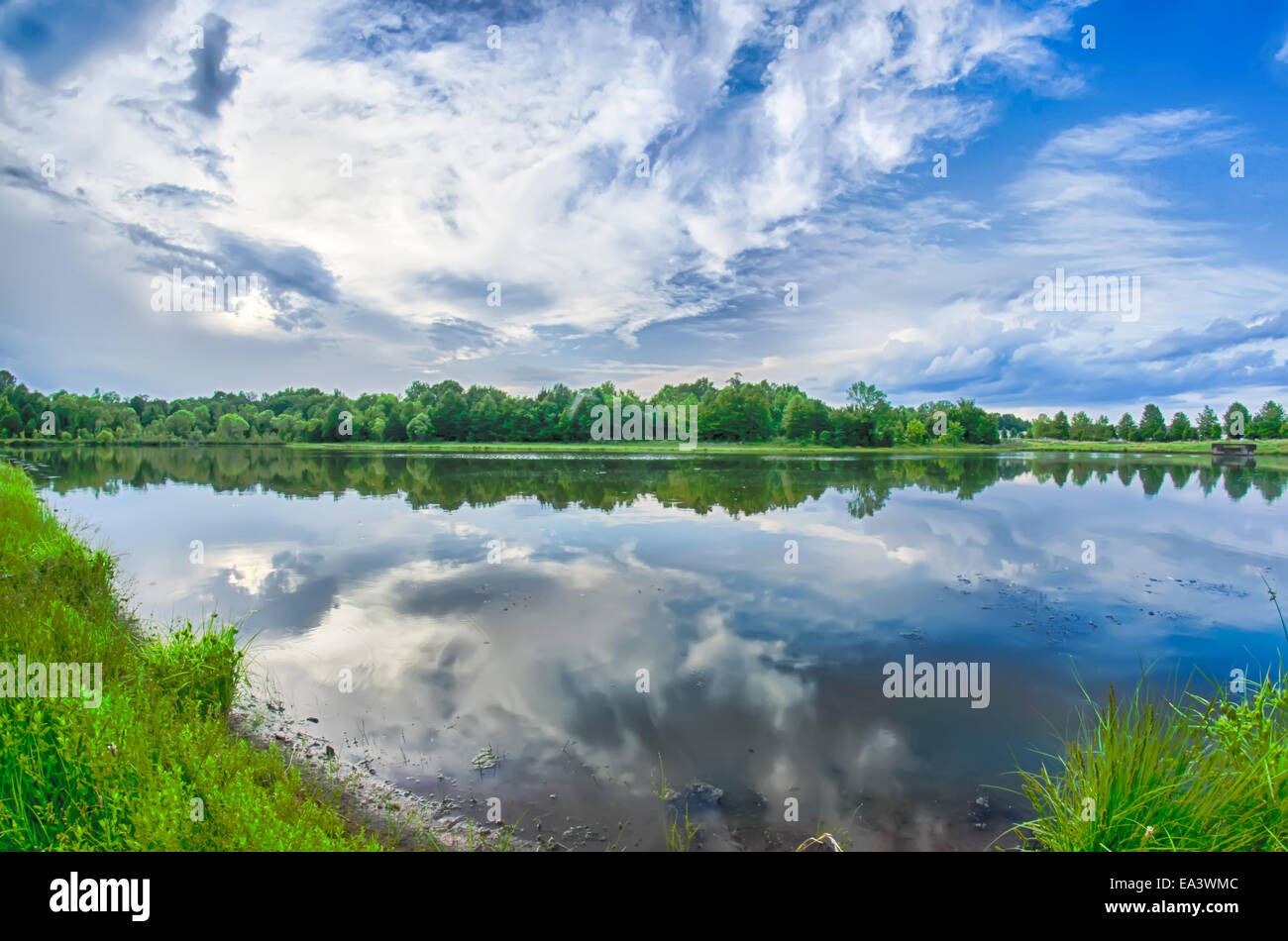 sun setting over a reflective lake Stock Photo - Alamy