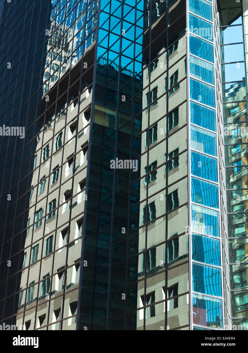 An office tower reflects a residential building in the glass windows ...