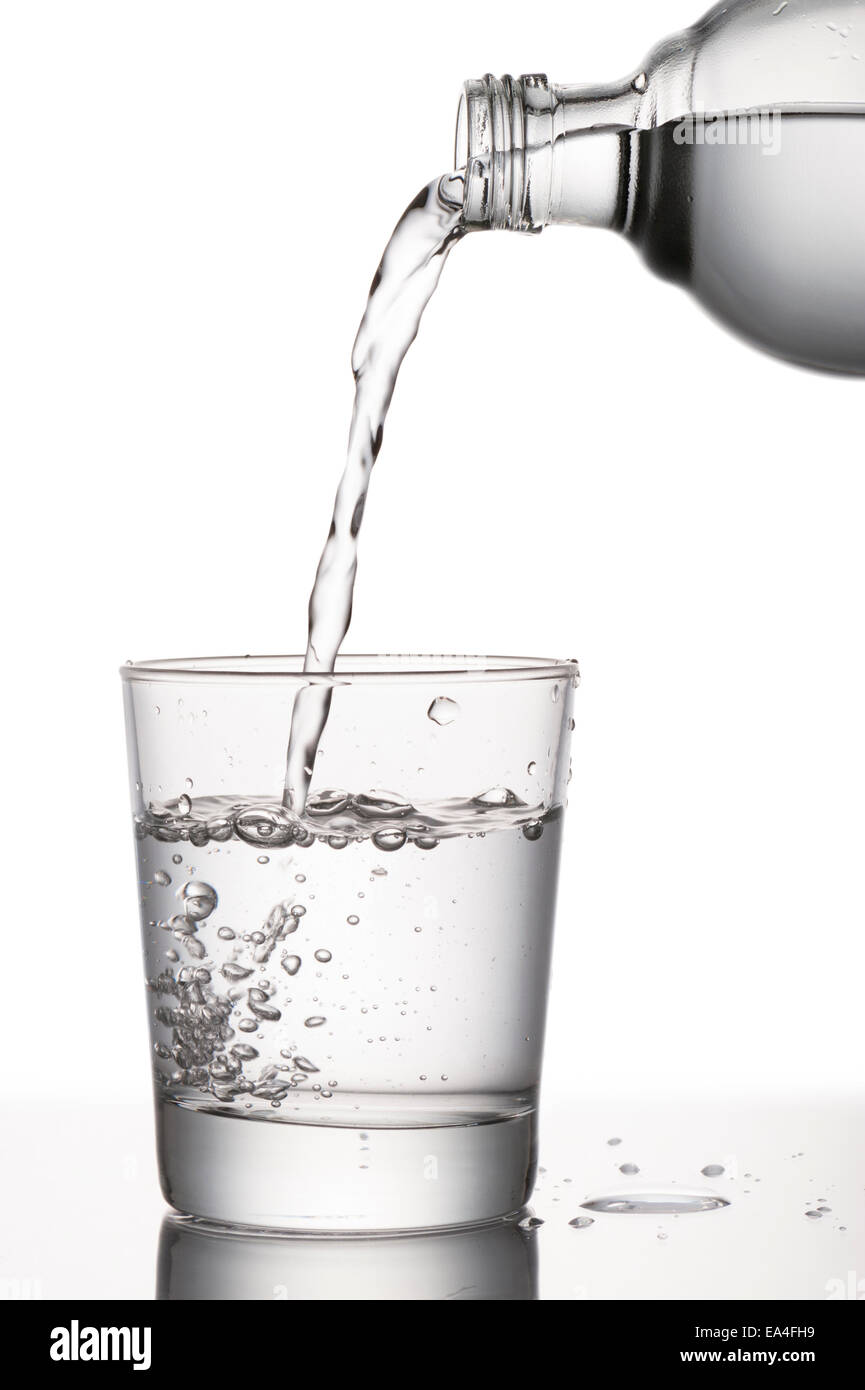 pouring water into glass from a bottle, on white background Stock Photo - Alamy