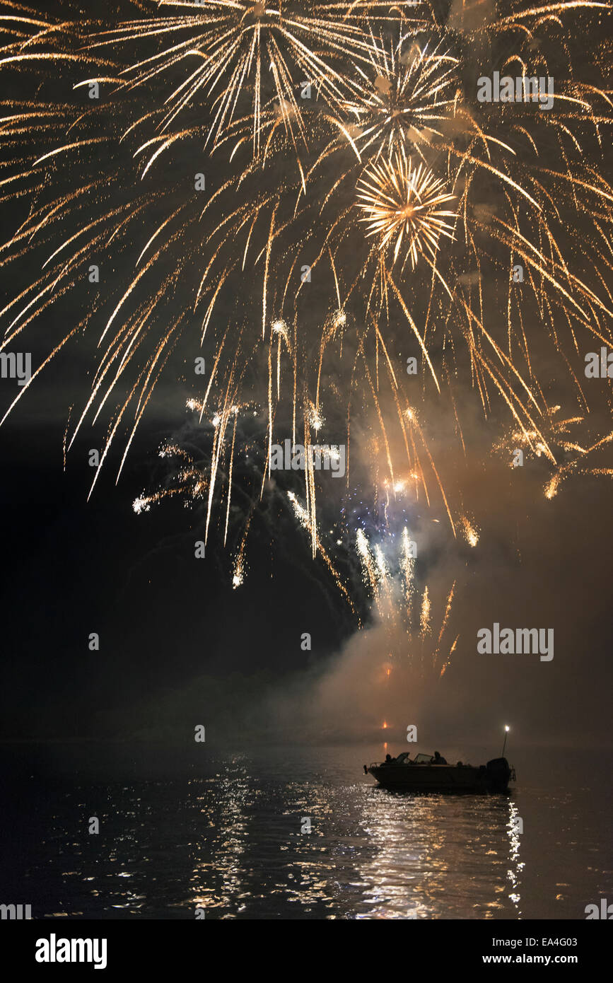 Fireworks display over a lake illuminating the boats on the water ...