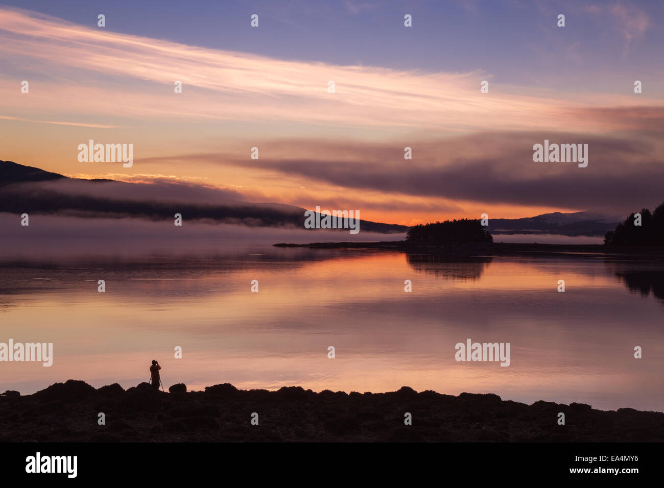 A hiker takes a break while walking along the beach, pausing to admire ...