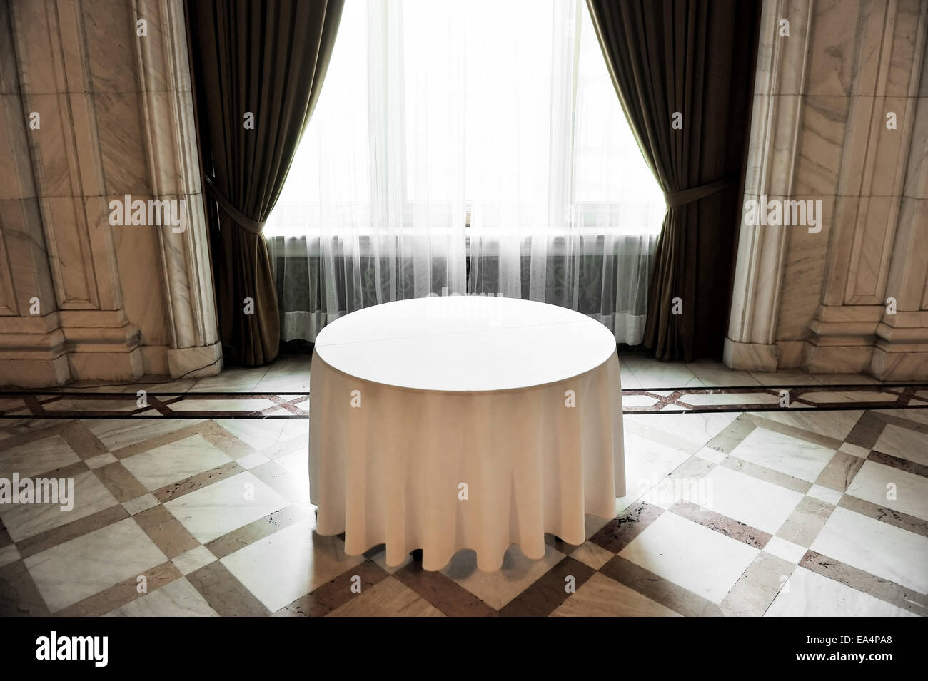 Sunlight falls on an empty round dinner table in a festive marble room ...