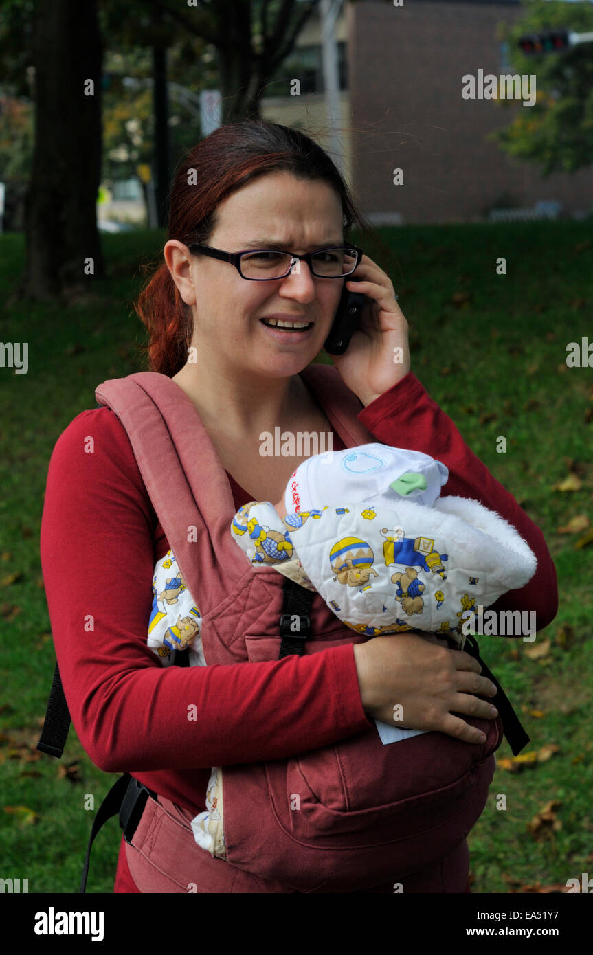 A mother carrying a baby and using a mobile phone Stock Photo - Alamy