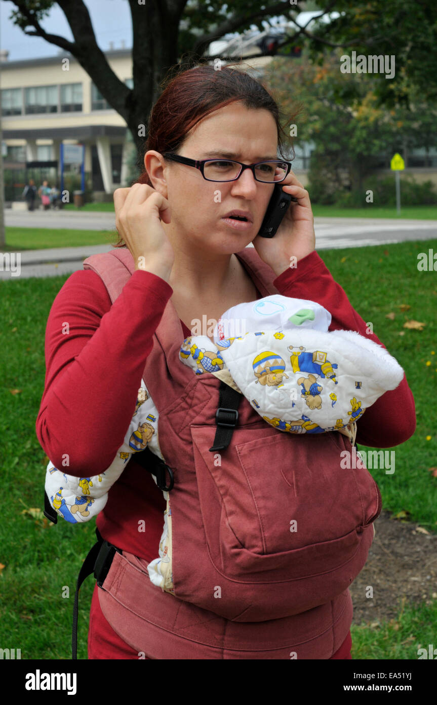 A mother carrying a baby and using a mobile phone Stock Photo - Alamy