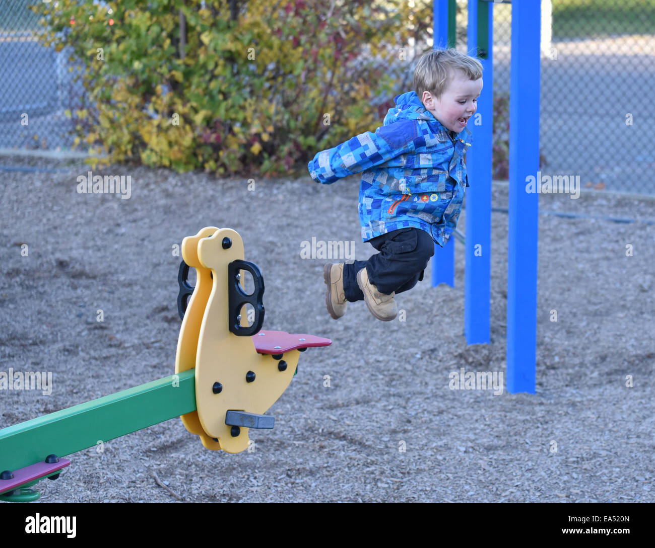 A young boy (2 1/2 yrs) jumping from a see-saw Stock Photo - Alamy
