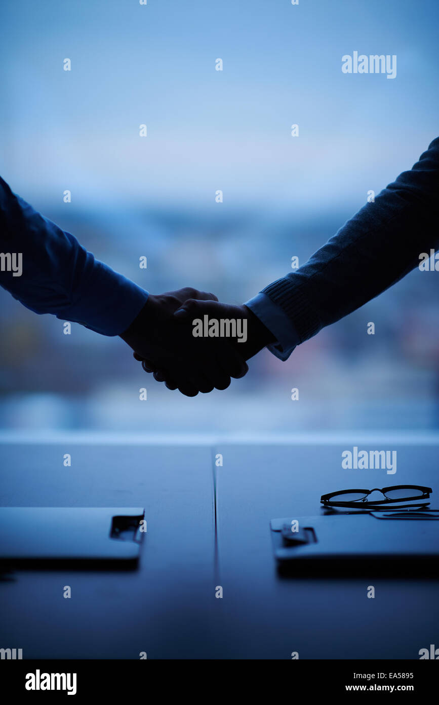 Outline of handshake of two businessmen over workplace after ...