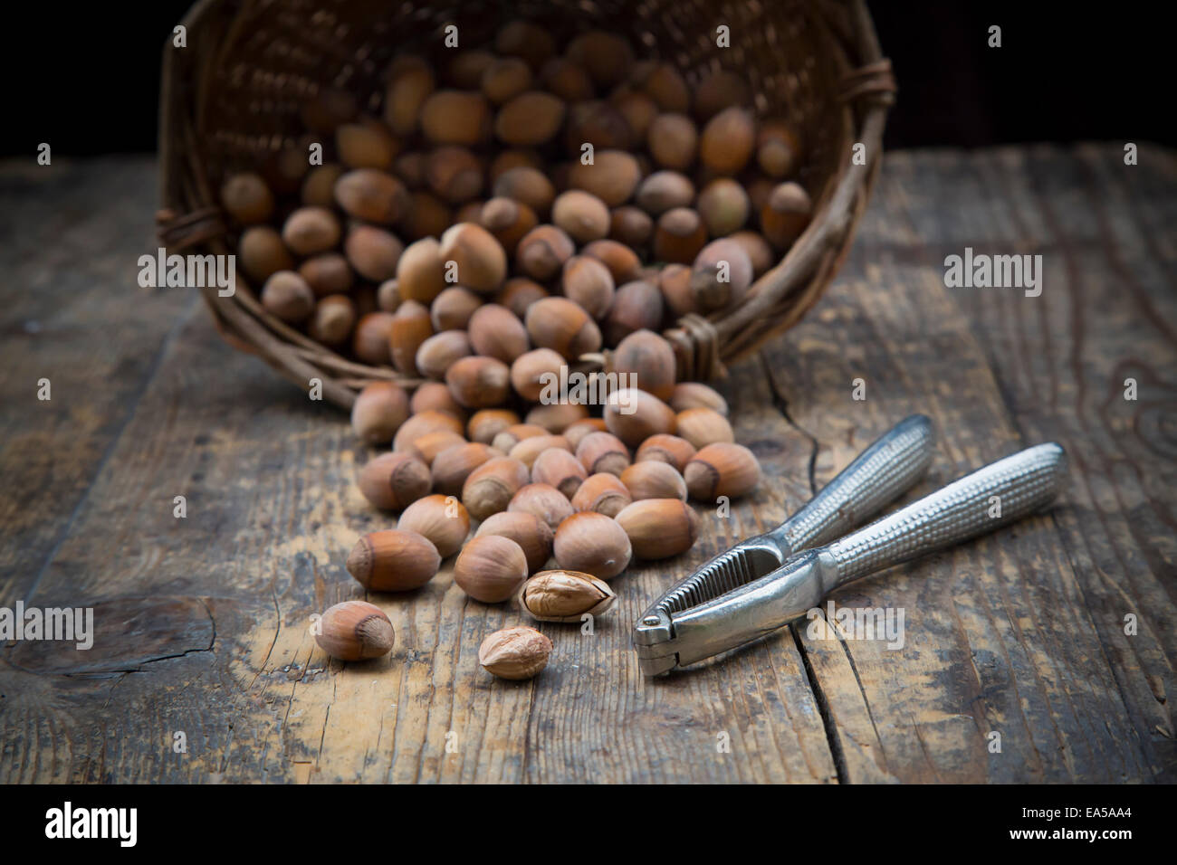 Wickerbasket of hazelnuts and nutcracker on dark wood Stock Photo - Alamy