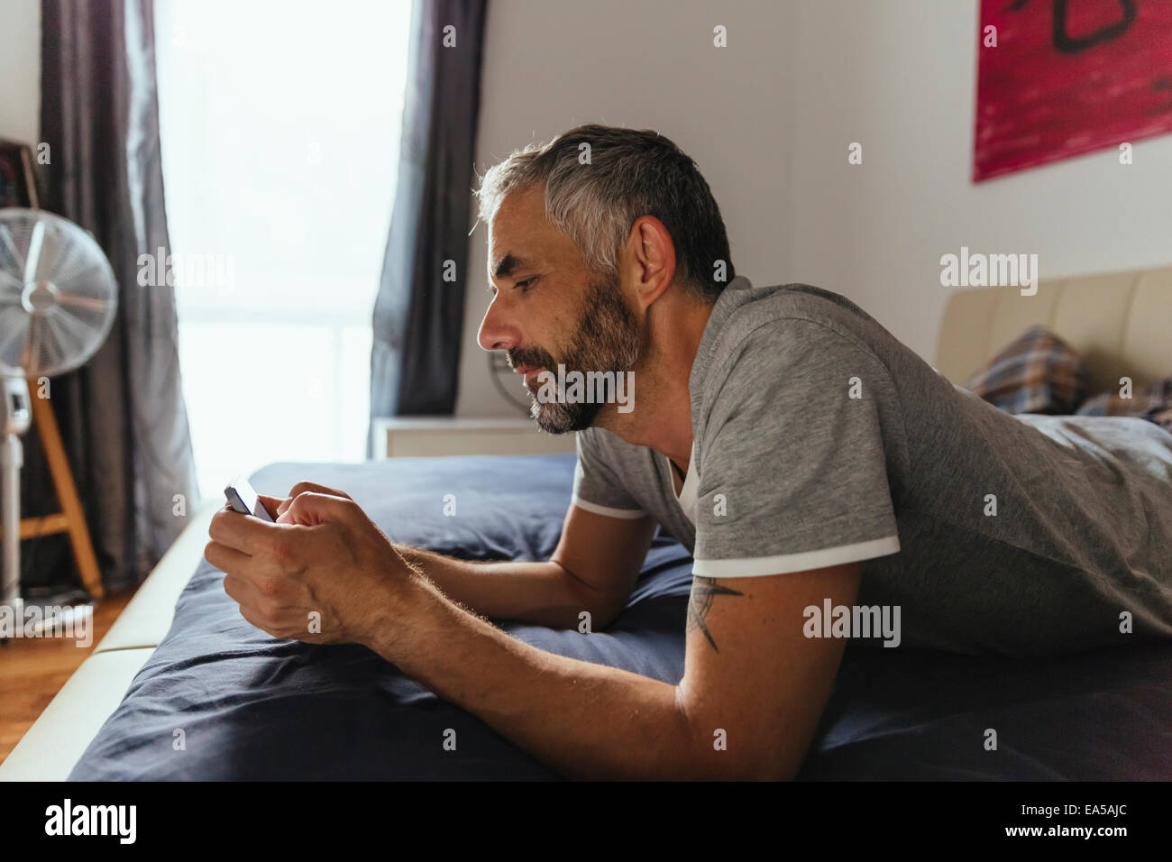 Man lying on his bed using his smartphone Stock Photo - Alamy