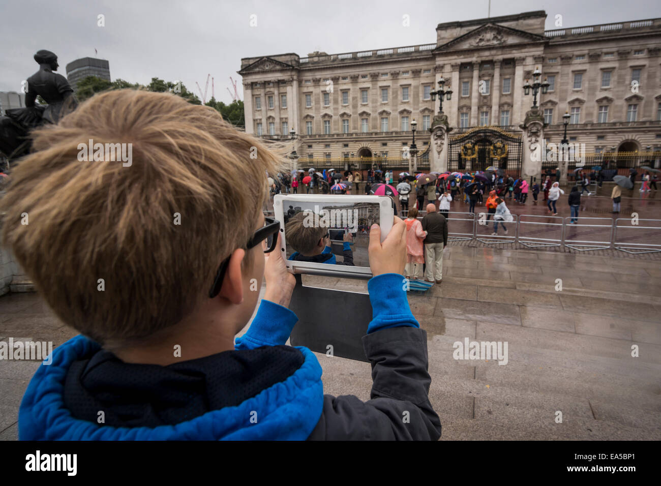 UK, London, boy photographing Buckingham Palace with his digital tablet ...