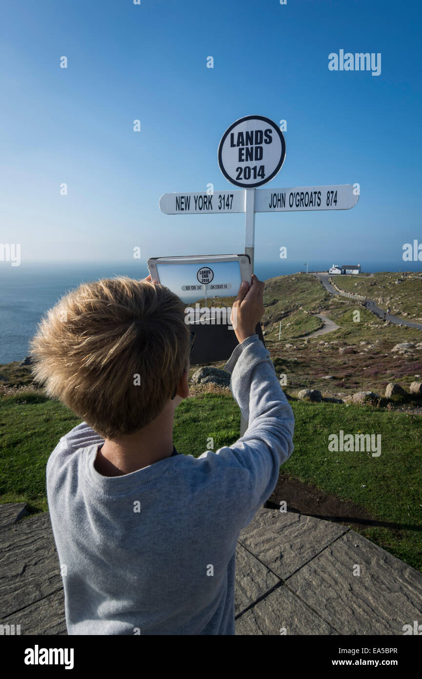 UK, Cornwall, boy photographing direction sign at Land's End with his ...