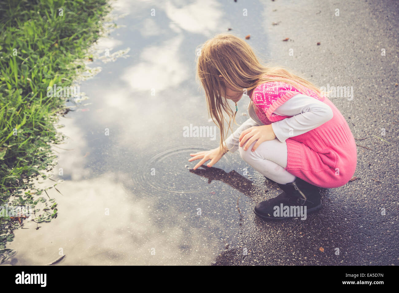 Little girl playing with water of a puddle Stock Photo - Alamy
