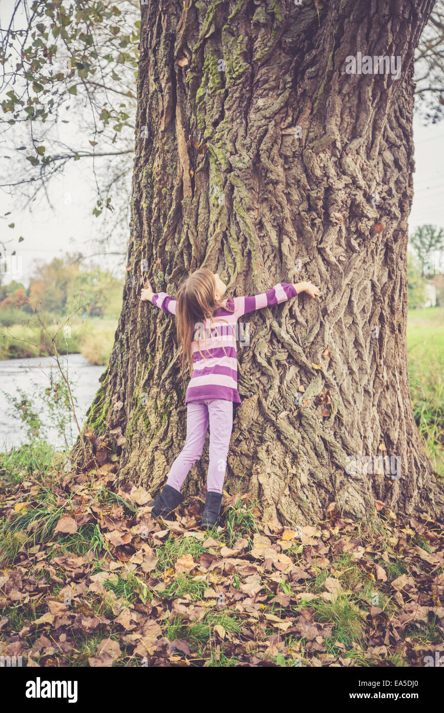 Little girl hugging old tree Stock Photo - Alamy