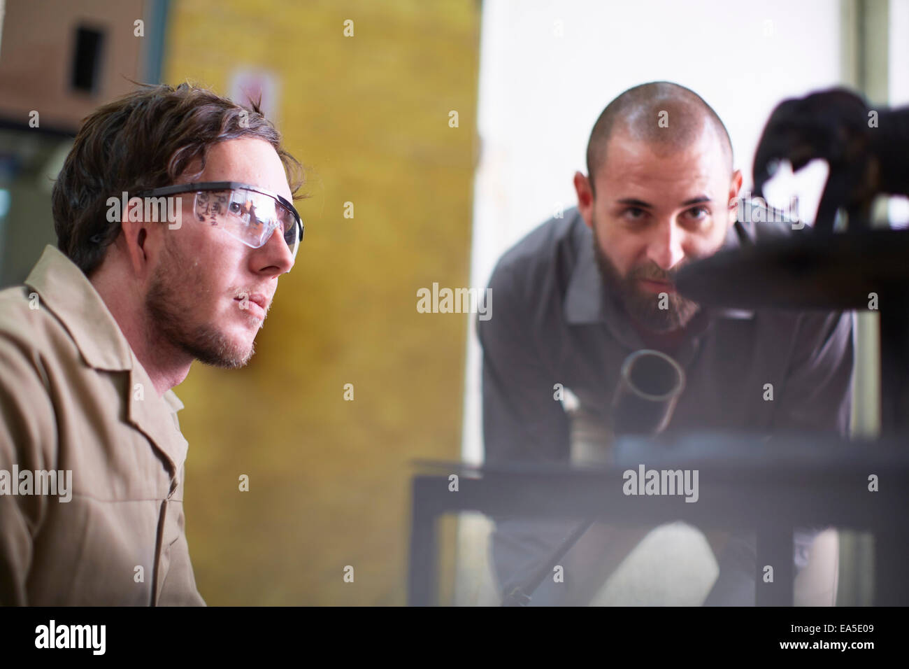 Two men in a sculptor's workshop looking at animal figurine Stock Photo ...