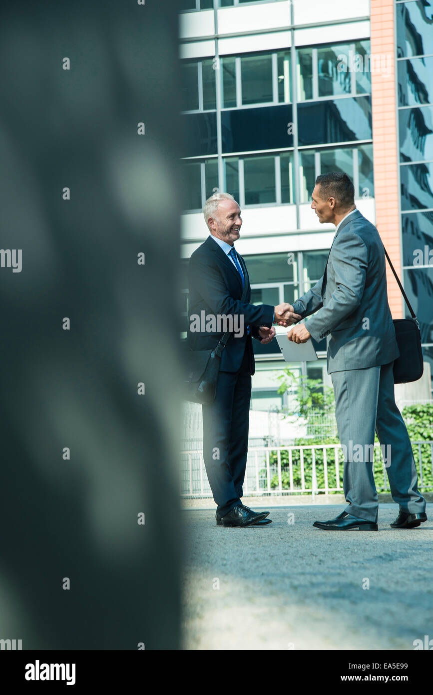 Two businessmen shaking hands outside office building Stock Photo - Alamy