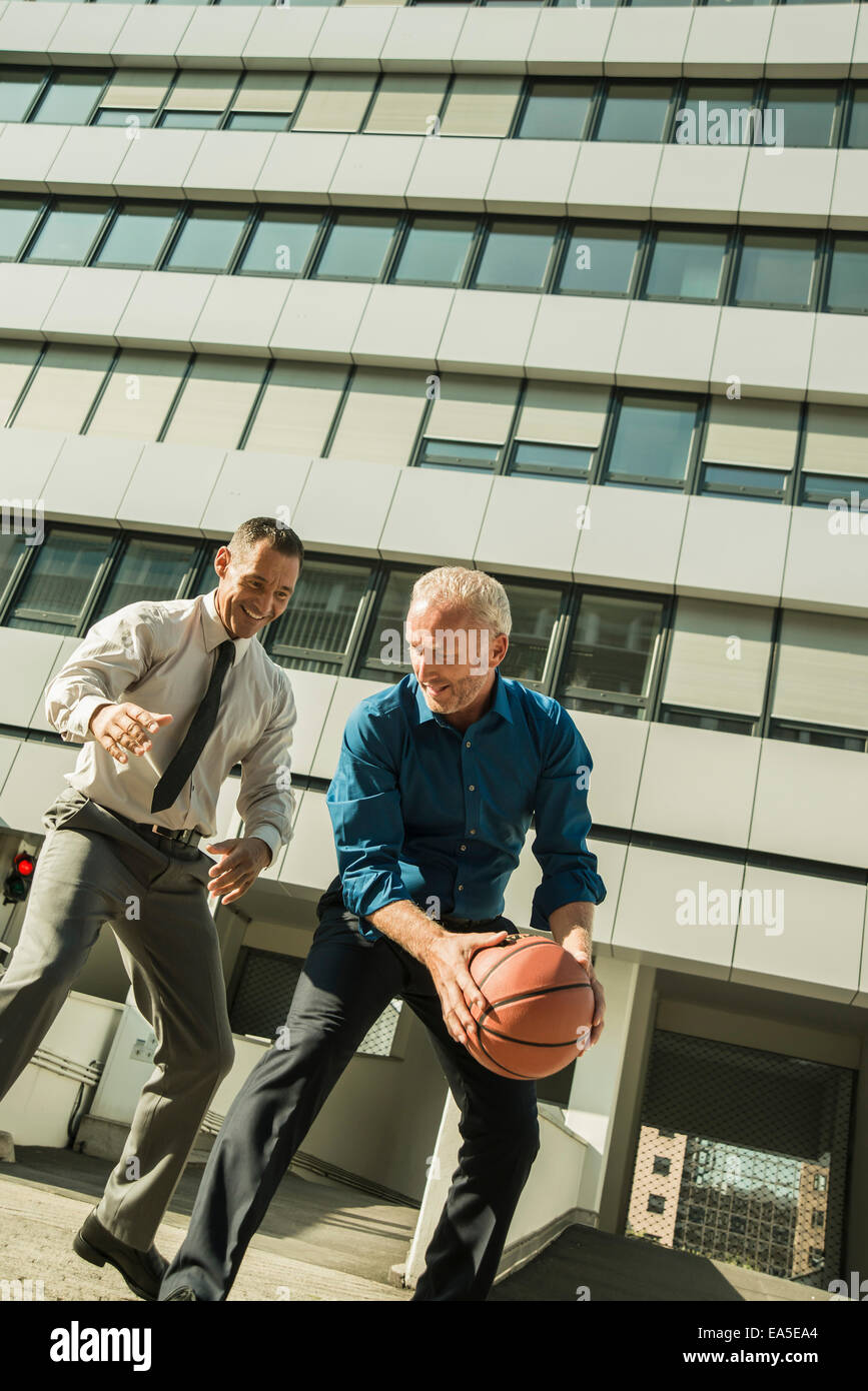Two businessmen playing basketball outside office building Stock Photo ...