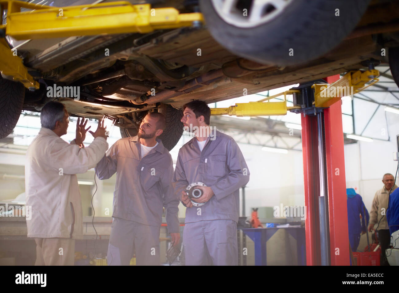 Two car mechanics with client in repair garage Stock Photo - Alamy