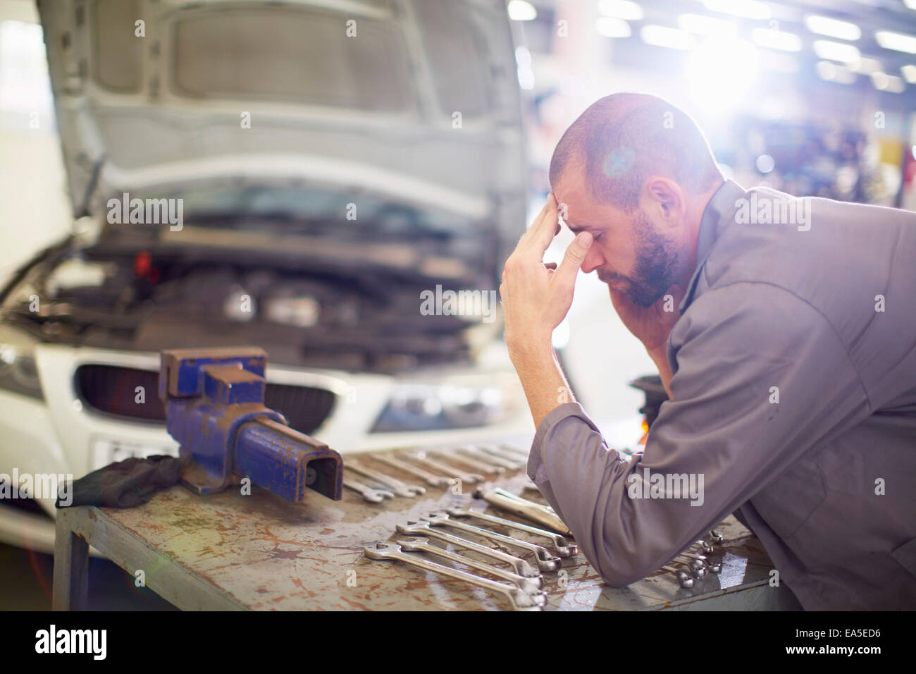 Stressed car mechanic in repair garage Stock Photo - Alamy