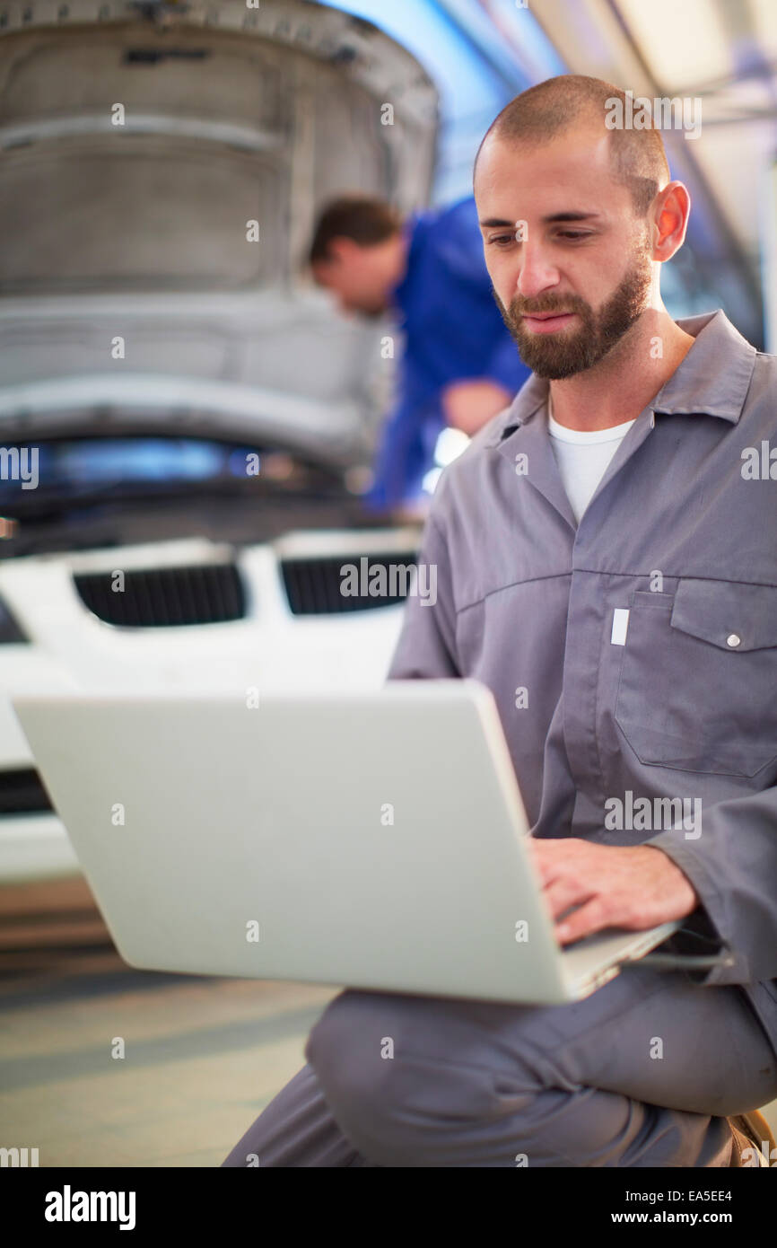 Car mechanic using laptop in repair garage Stock Photo - Alamy