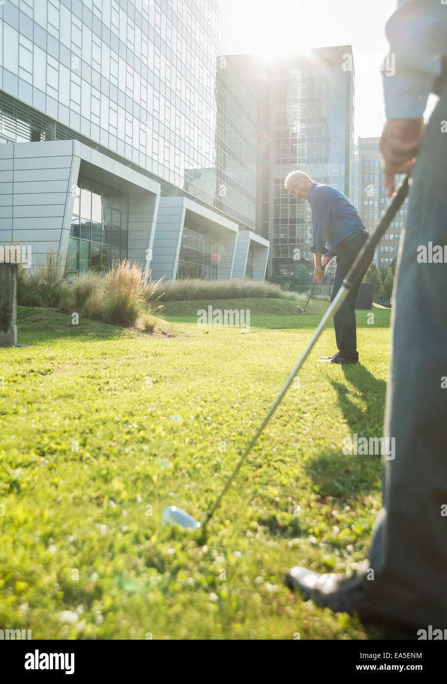 Two businessmen playing golf outside office building Stock Photo - Alamy