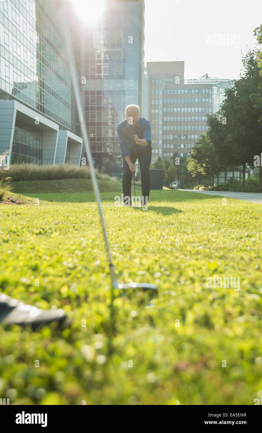 Two businessmen playing golf outside office building Stock Photo - Alamy