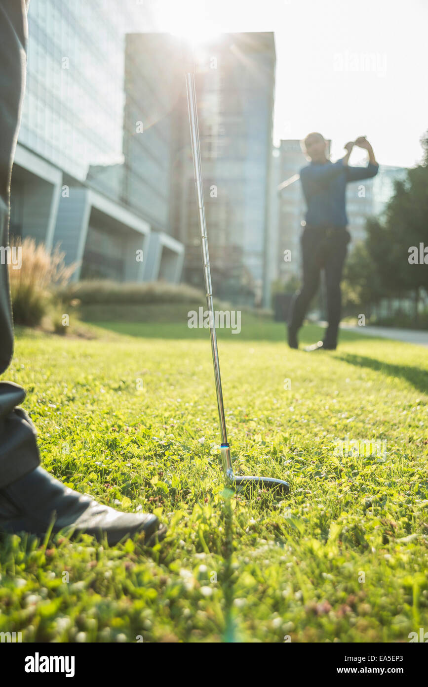 Two businessmen playing golf outside office building Stock Photo - Alamy