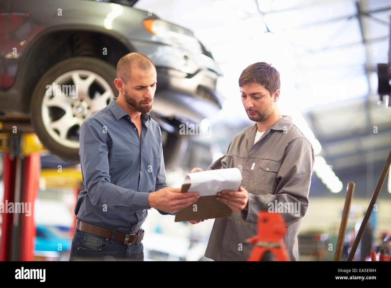 Car mechanic with client in repair garage Stock Photo - Alamy