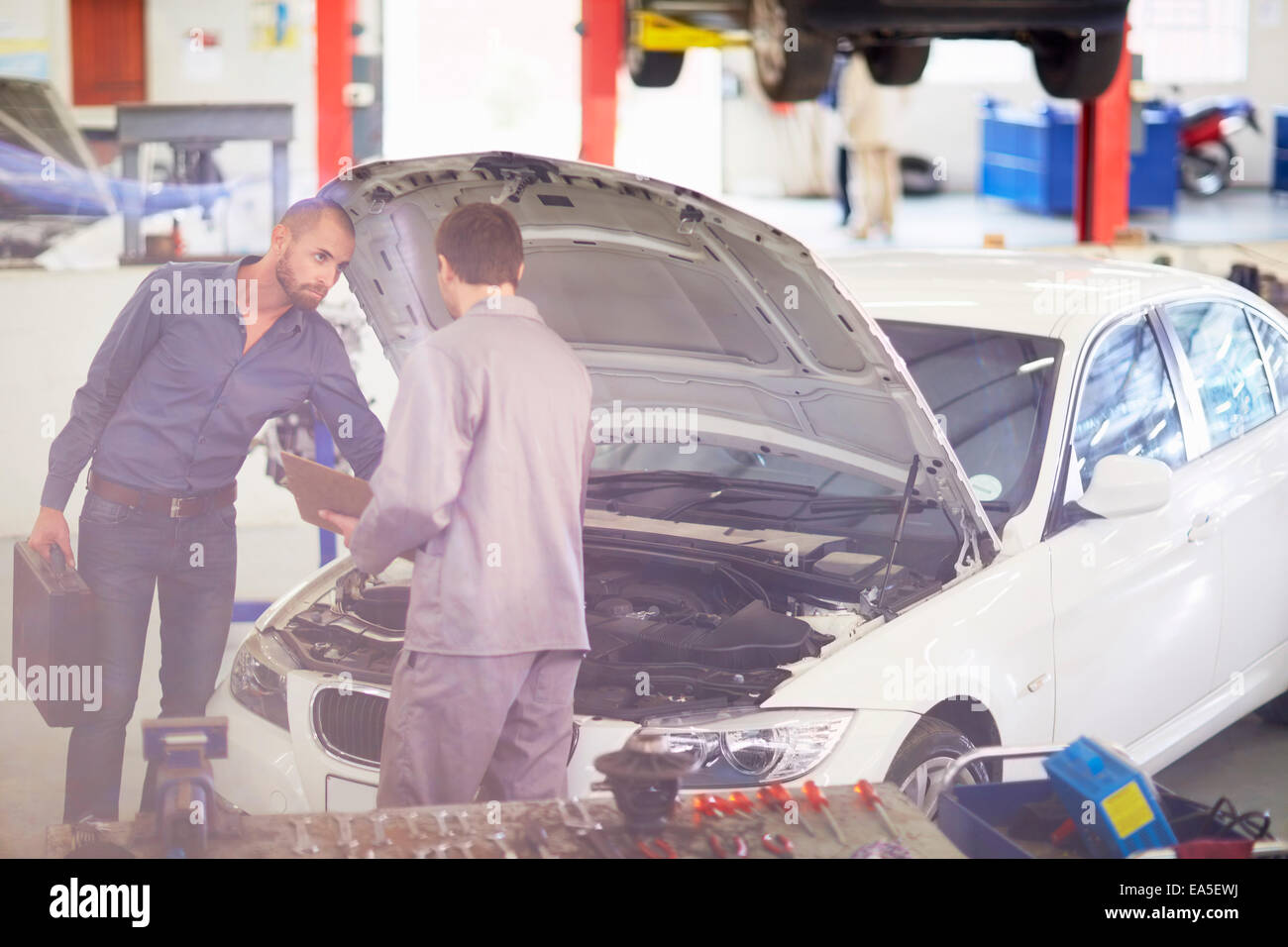 Car mechanic with client in repair garage Stock Photo - Alamy