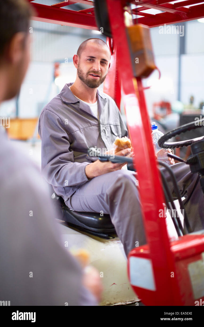Worker on forklift in factory having lunch break Stock Photo - Alamy