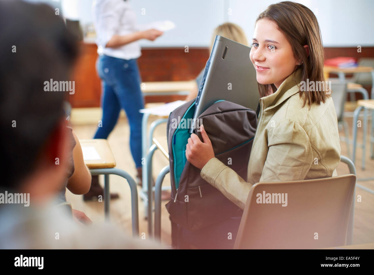 Student packing laptop into backpack in classroom Stock Photo - Alamy