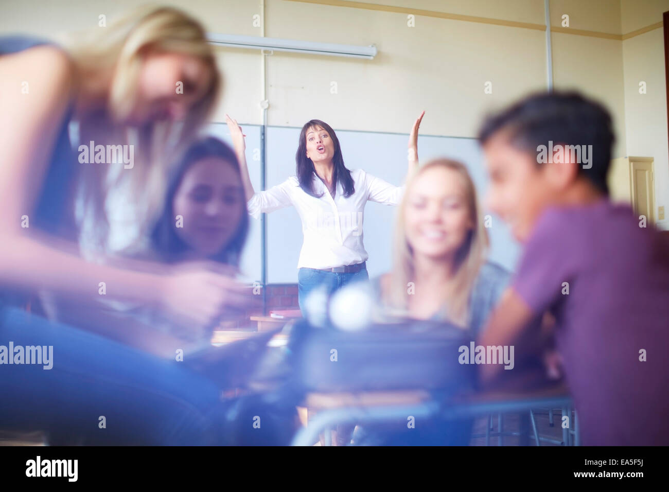 Frustrated teacher and talking students in classroom Stock Photo - Alamy