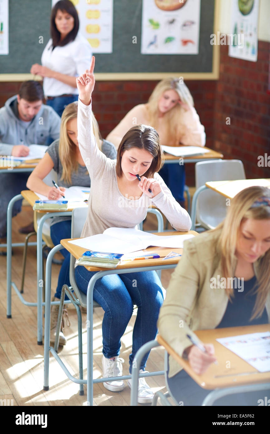 Female student in classroom raising her hand Stock Photo - Alamy