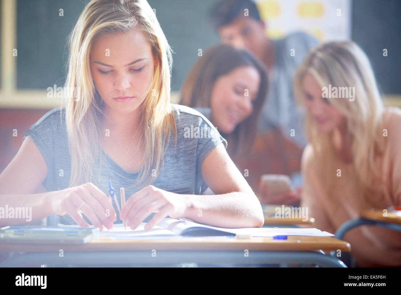 Female student in classroom using compasses at desk Stock Photo - Alamy