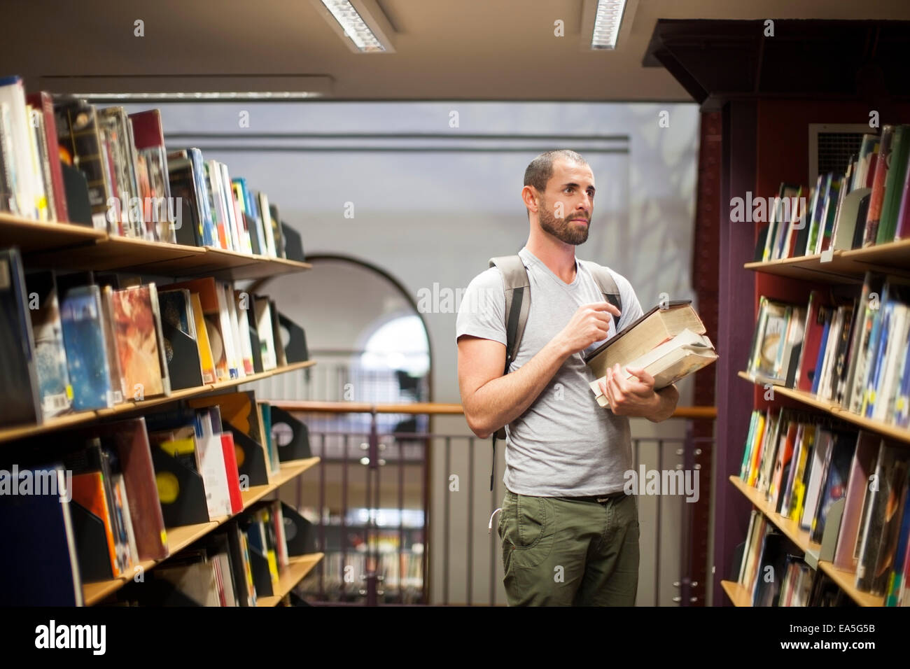 Student in a library at bookshelf Stock Photo - Alamy