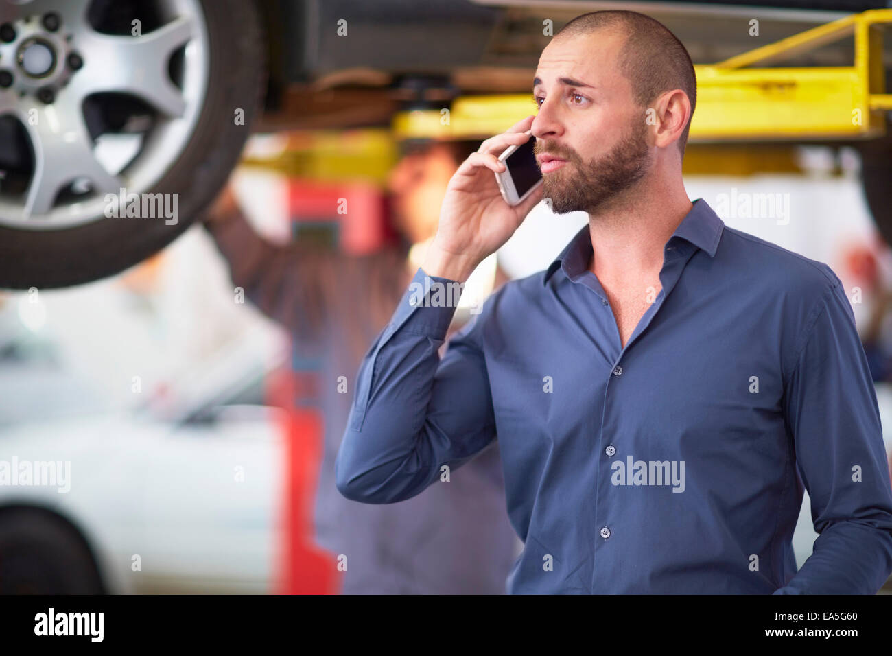 Client on cell phone in repair garage Stock Photo - Alamy