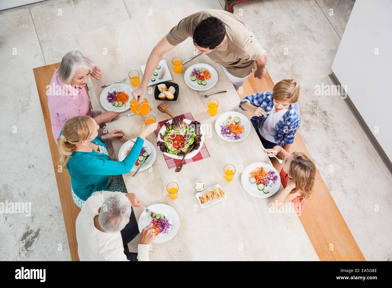 Extended family with salad and juice at dining table Stock Photo - Alamy