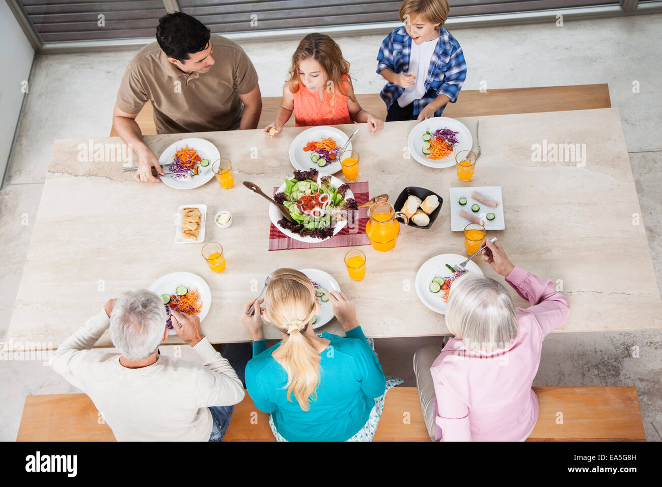 Extended family with salad and juice at dining table Stock Photo - Alamy
