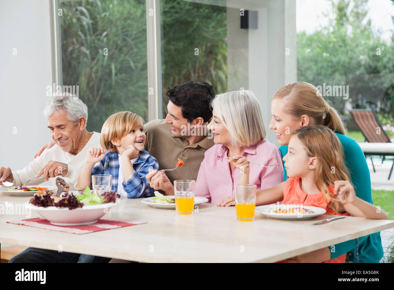 Extended family with salad and juice at dining table Stock Photo - Alamy