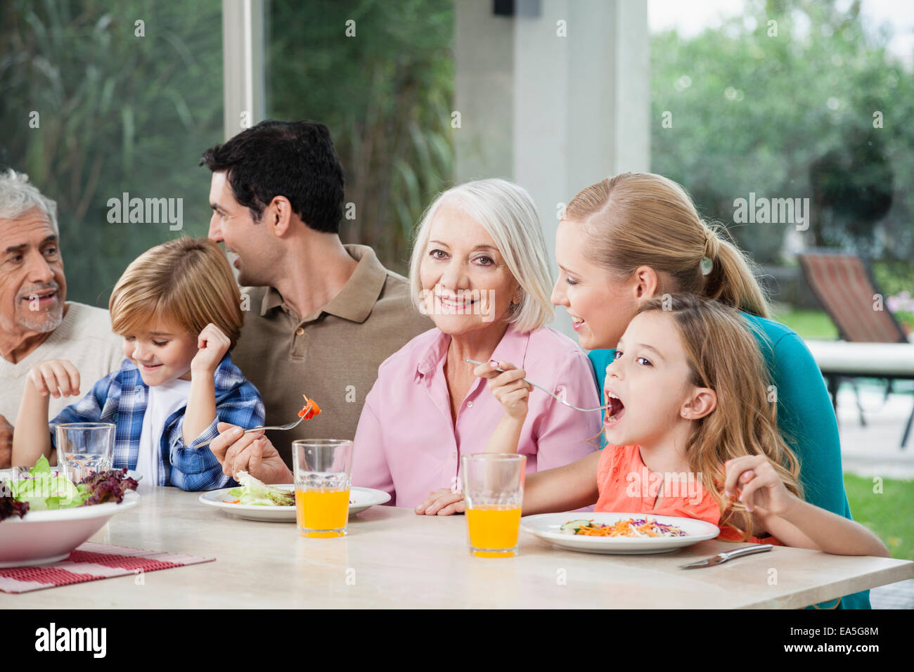 Extended family with salad and juice at dining table Stock Photo - Alamy