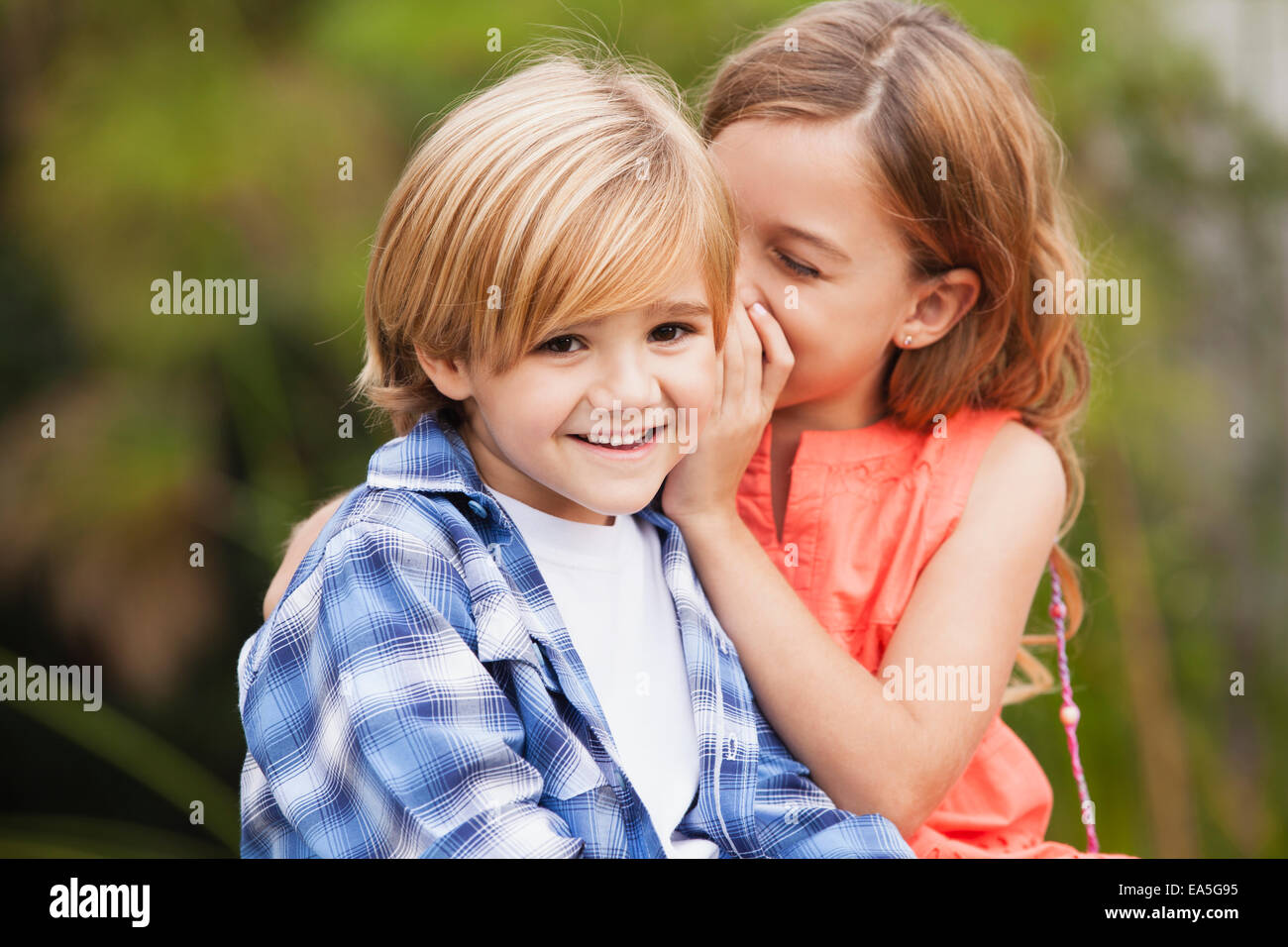 Girl whispering into boy's ear Stock Photo - Alamy