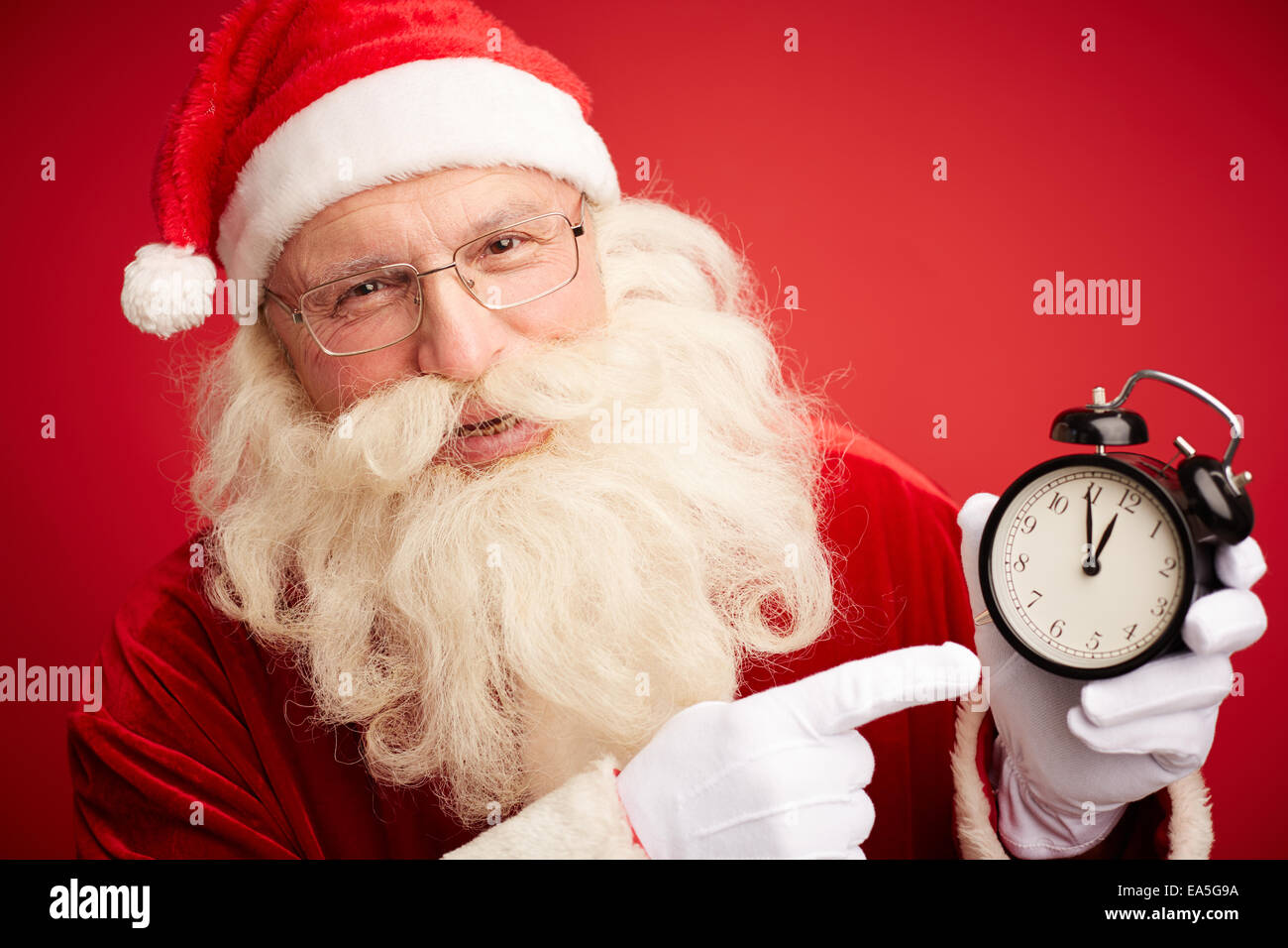 Smiling Santa holding clock showing five minutes to twelve Stock Photo ...