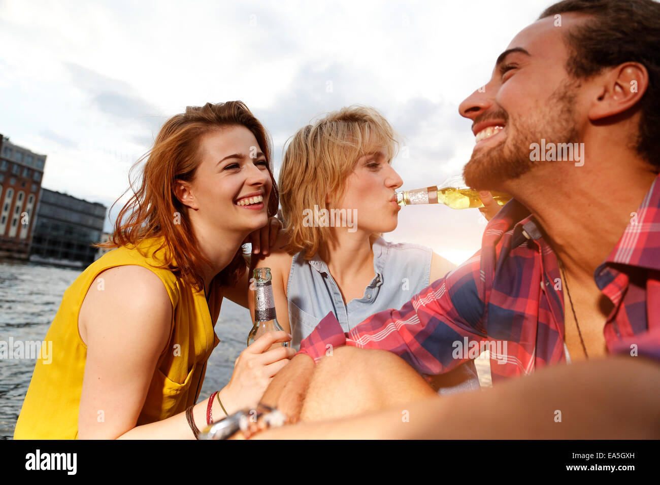 Germany, Berlin, Friend sitting at Spree river, drinking beer Stock ...