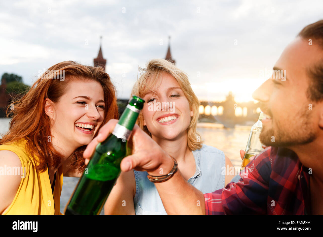 Germany, Berlin, Friend sitting at Spree river, drinking beer Stock ...