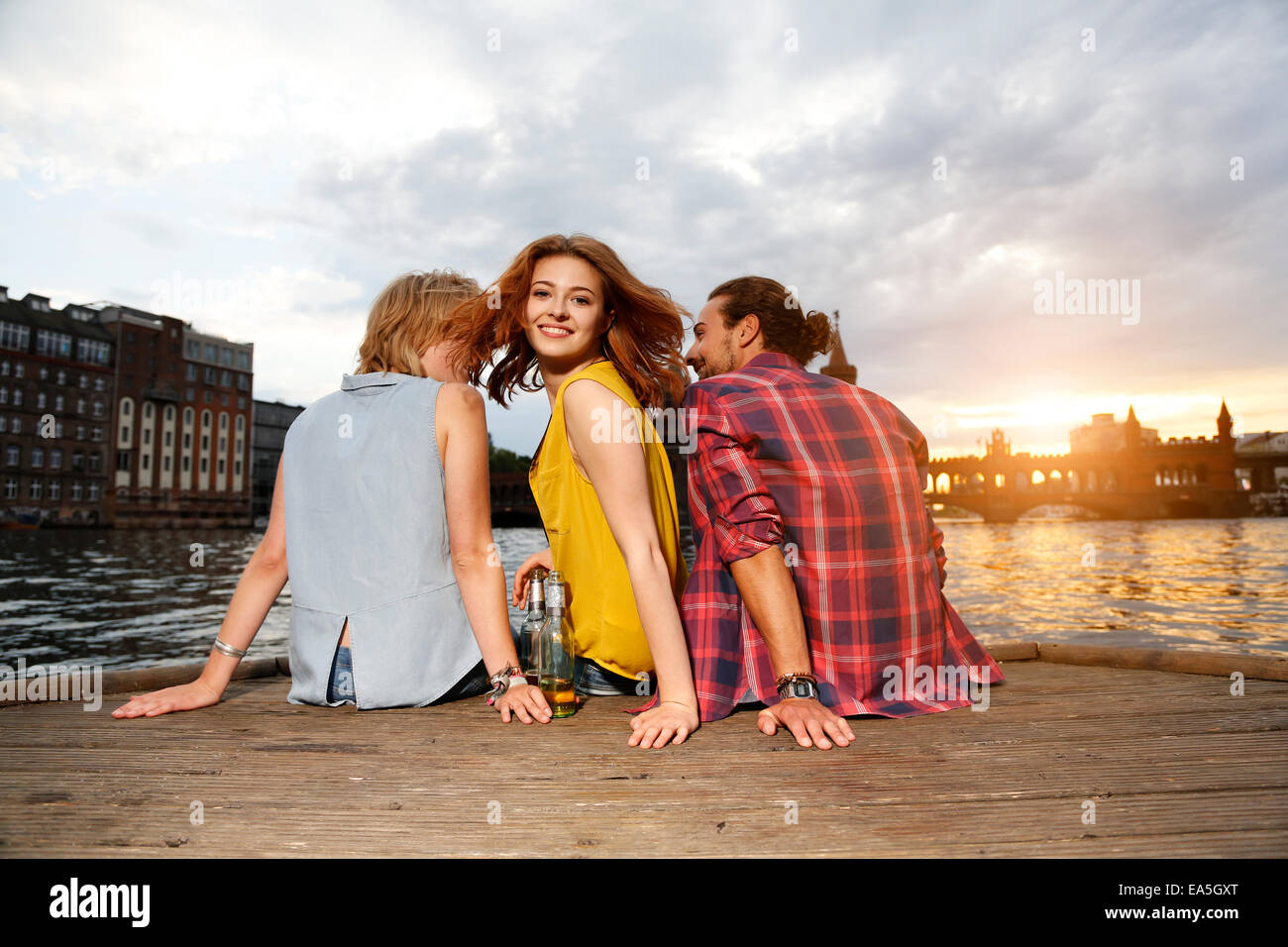 Germany, Berlin, Friend sitting at Spree river, enjoying sunset Stock ...